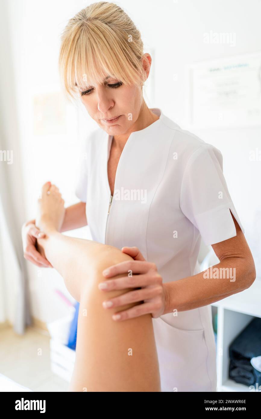 Blond haired osteopath treating leg of woman Stock Photo - Alamy