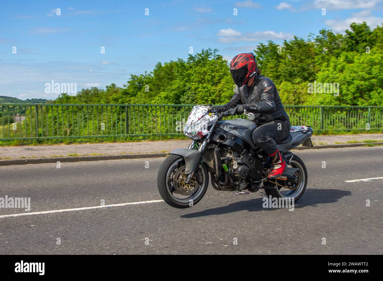 Grey Kawasaki motorcycle crossing motorway bridge with raised front ...