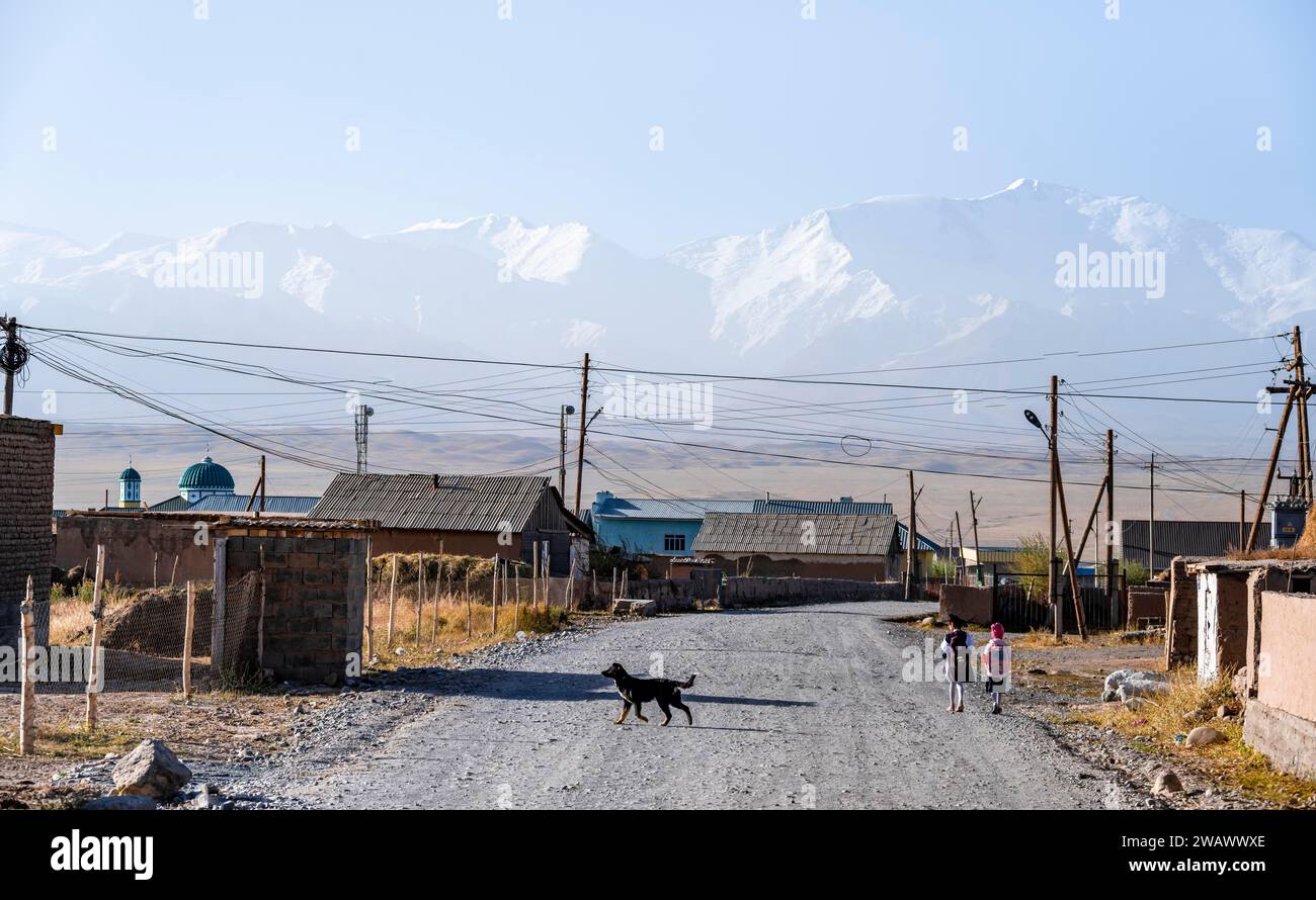 Schoolchildren and dog in the village of Sary Mogul, snow-capped ...