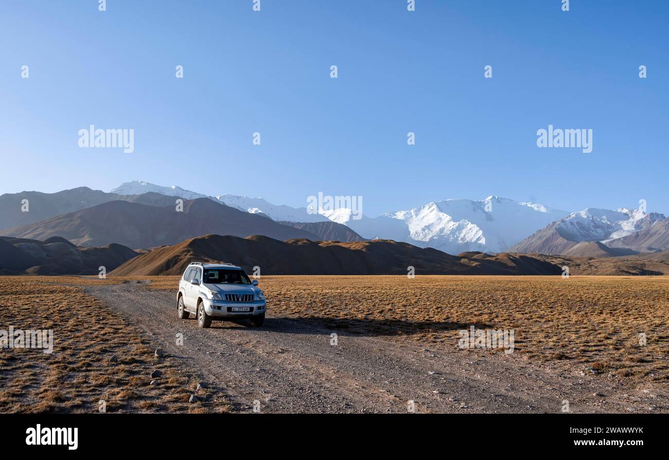 Off-road vehicle in front of snow-covered mountains, Pamir Mountains ...