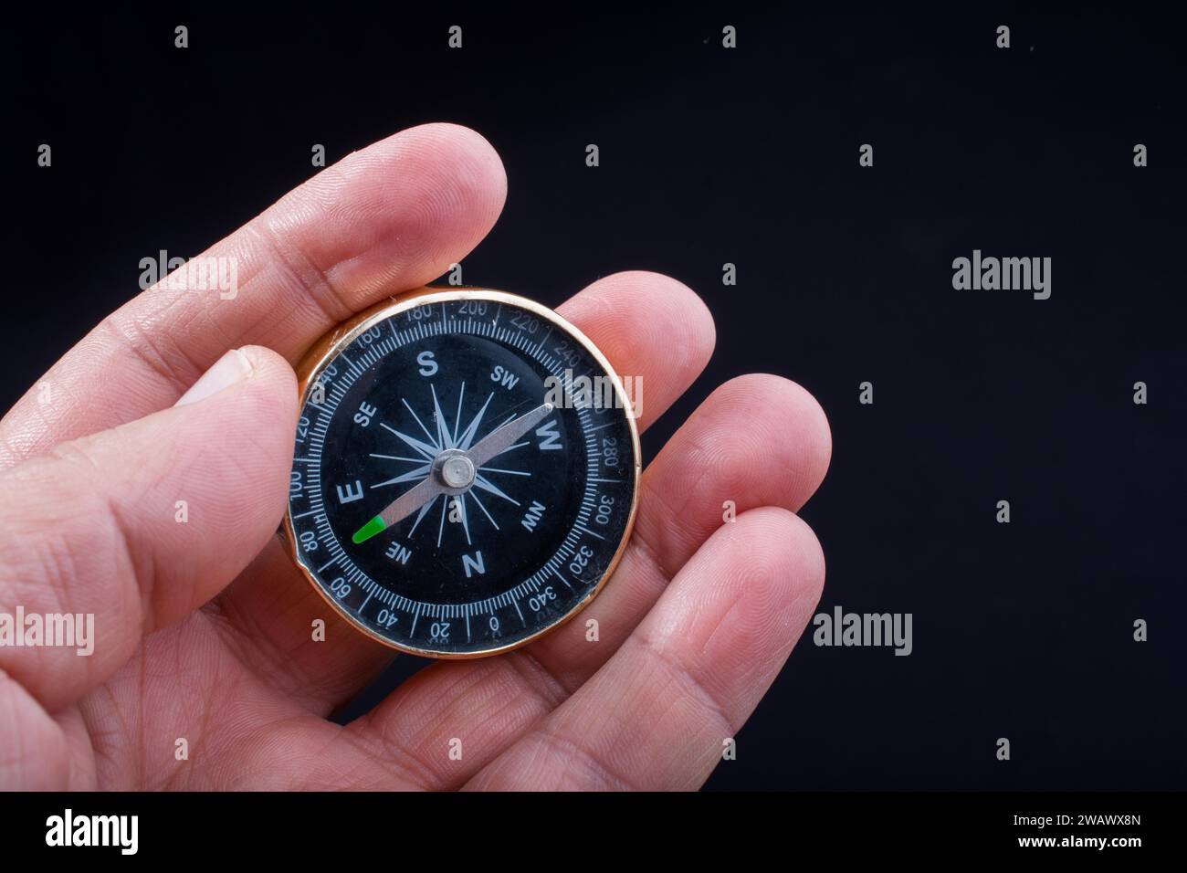 Child hand holding a compass on a black background Stock Photo - Alamy