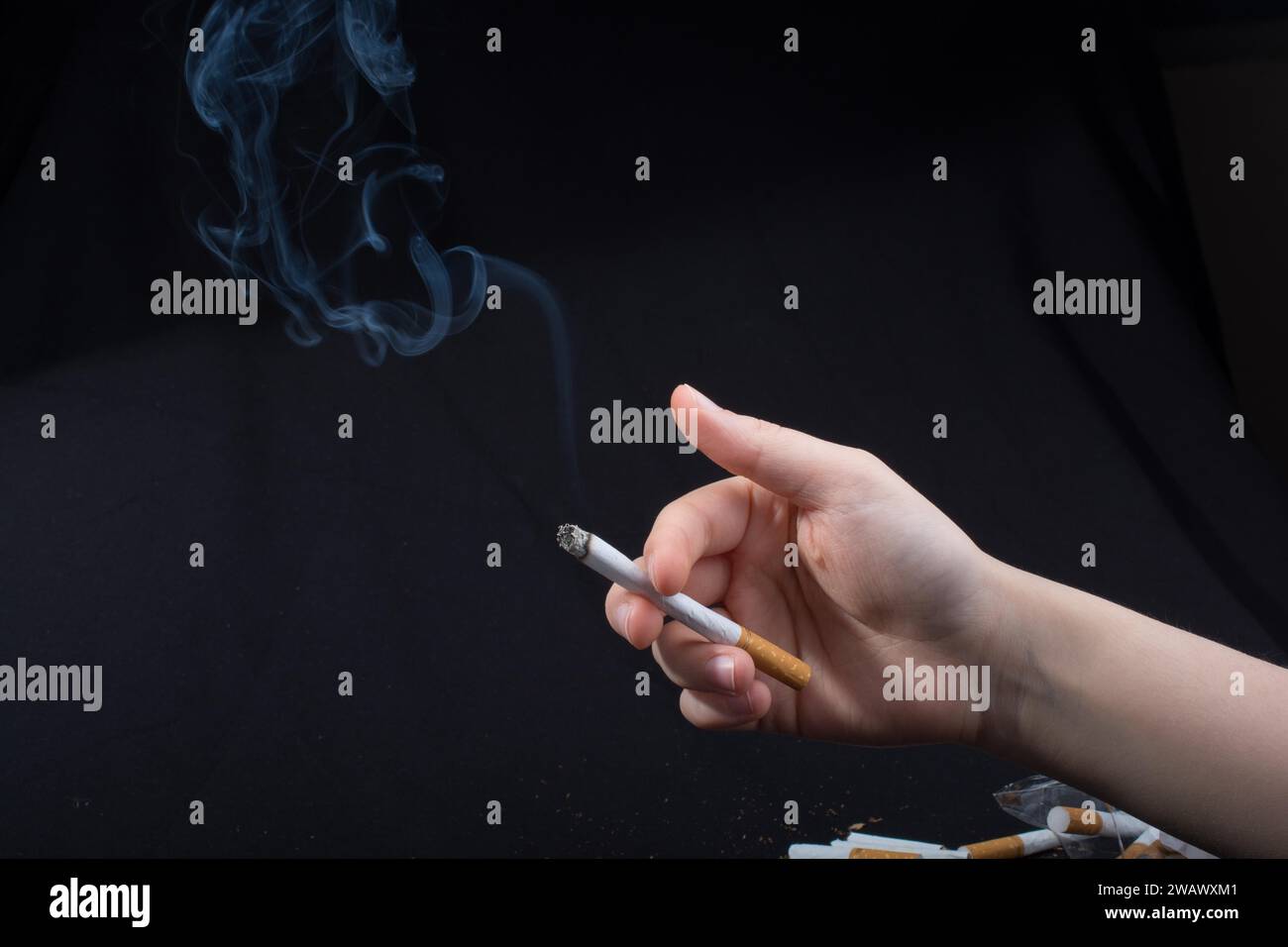 Hand is holding smoking cigarette with smoke around Stock Photo - Alamy