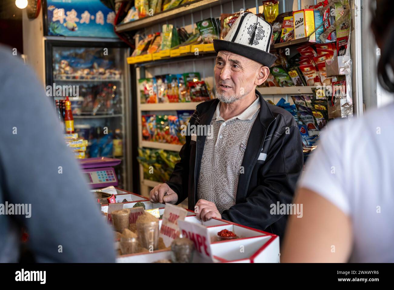 Man with traditional hat selling food, market at Osh bazaar, Bishkek ...