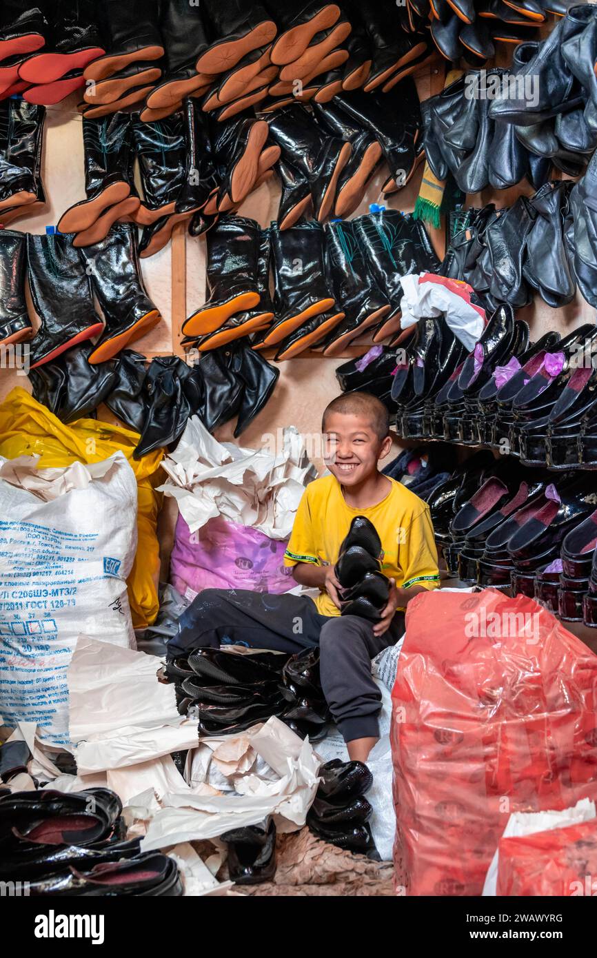 Boy selling shoes, shoe seller, many shoes, market stall, Uzgen Bazaar ...