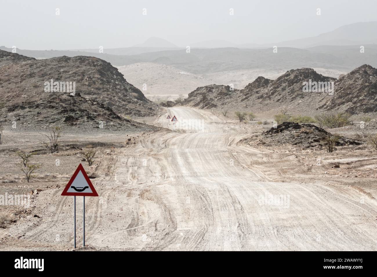 A warning sign stands in front of a sandy desert road, Safari ...