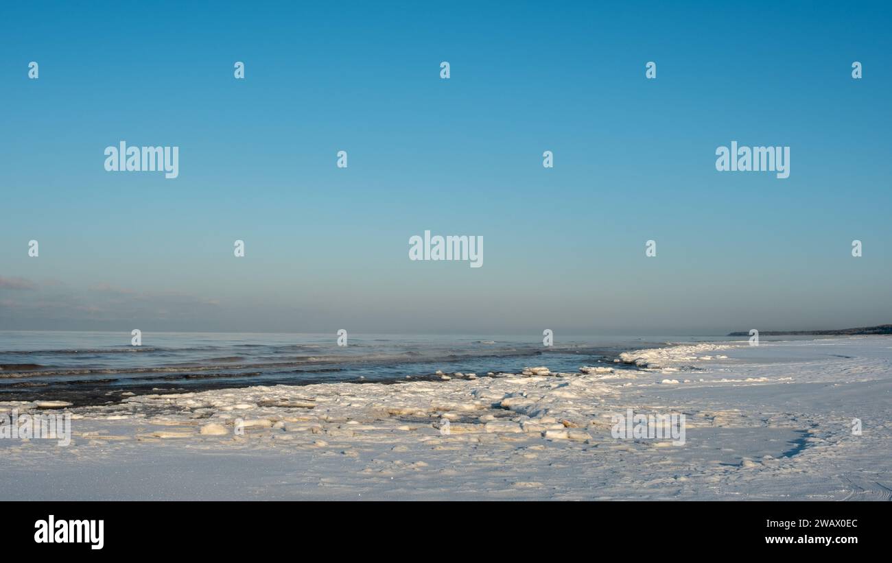 Amidst winter's chill, the sea and snow unite under the warm embrace of ...