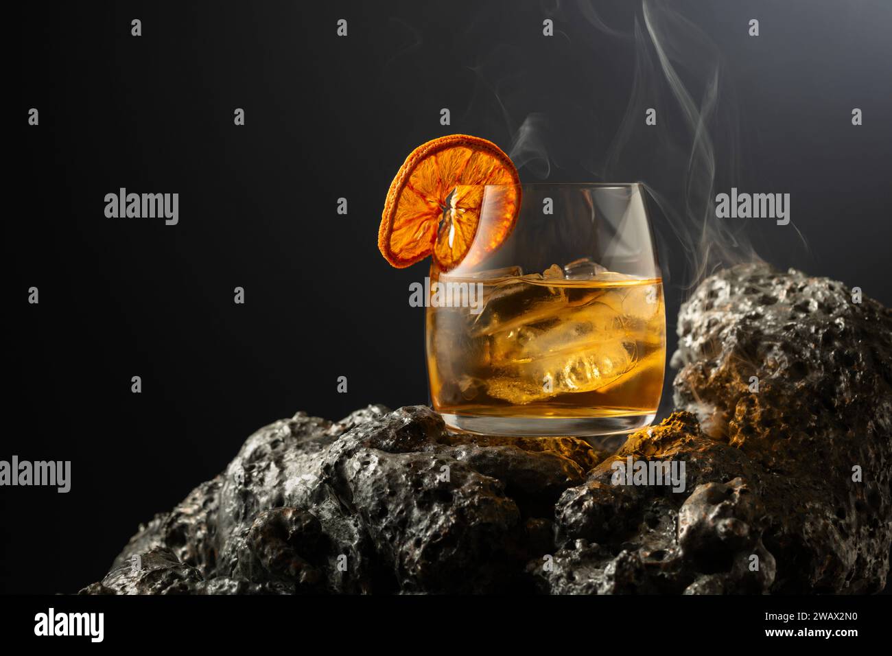 Smoked old fashioned rum cocktail with ice and dried orange slice on a ...
