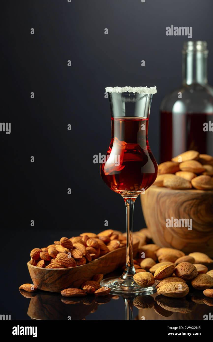 Strong alcoholic Italian liqueur Amaretto with almonds nuts on a black ...