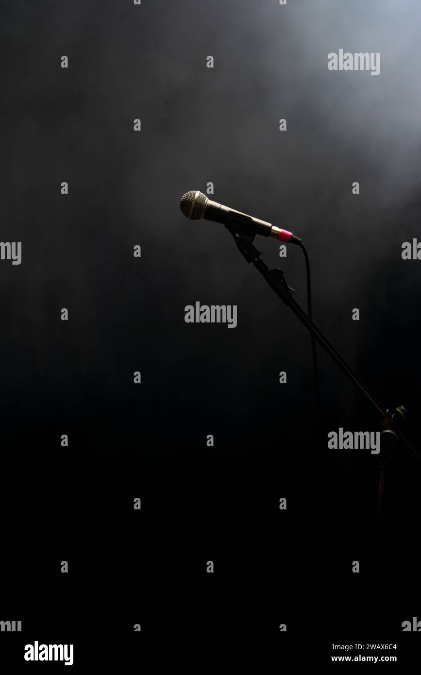Microphone on a tripod on a stage, illuminated with a light from above ...