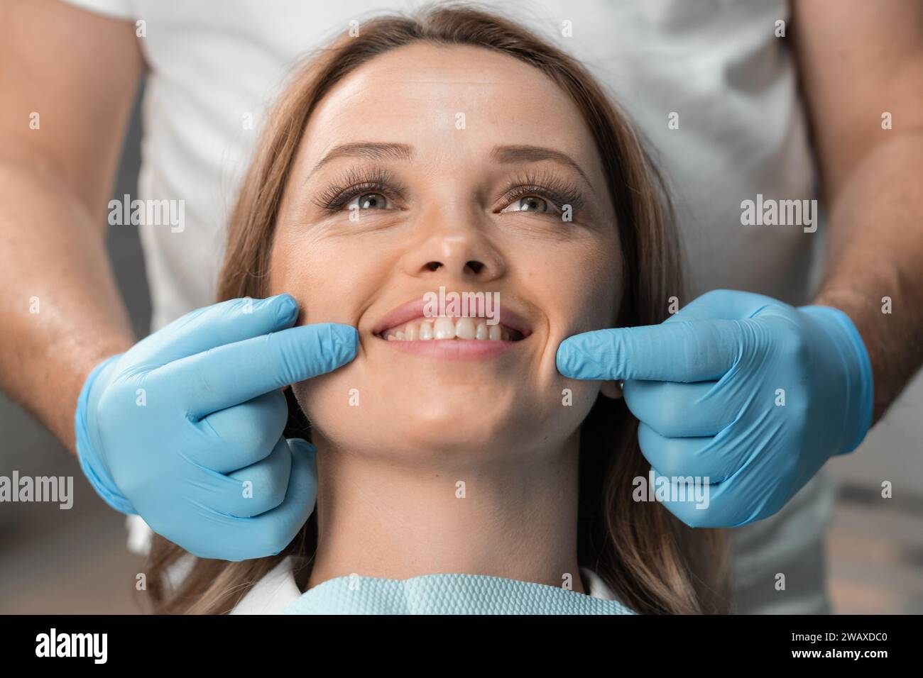 A woman sits in a dental chair, happily demonstrating her bright smile ...