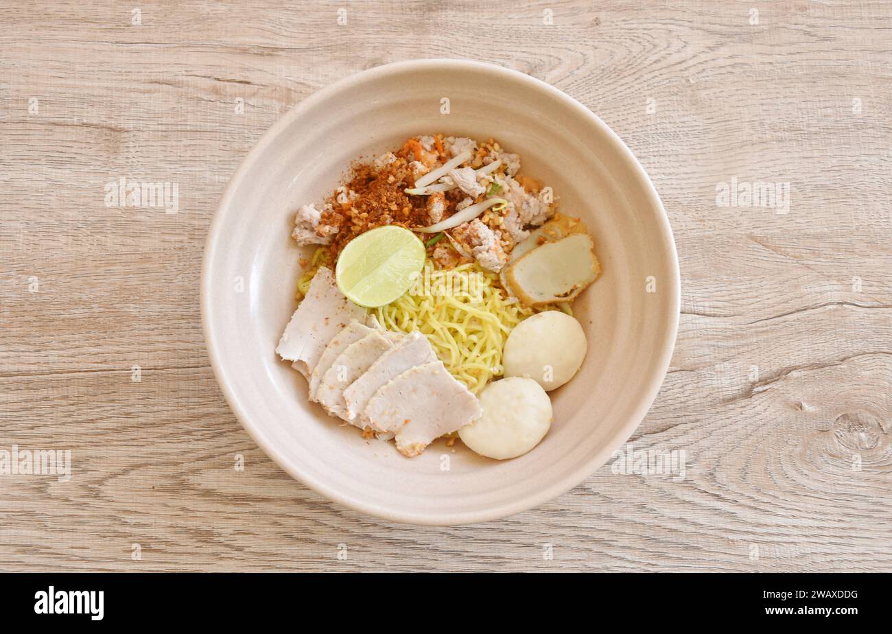 dry spicy tom yum Chinese yellow egg noodles with slice pork and ball ...