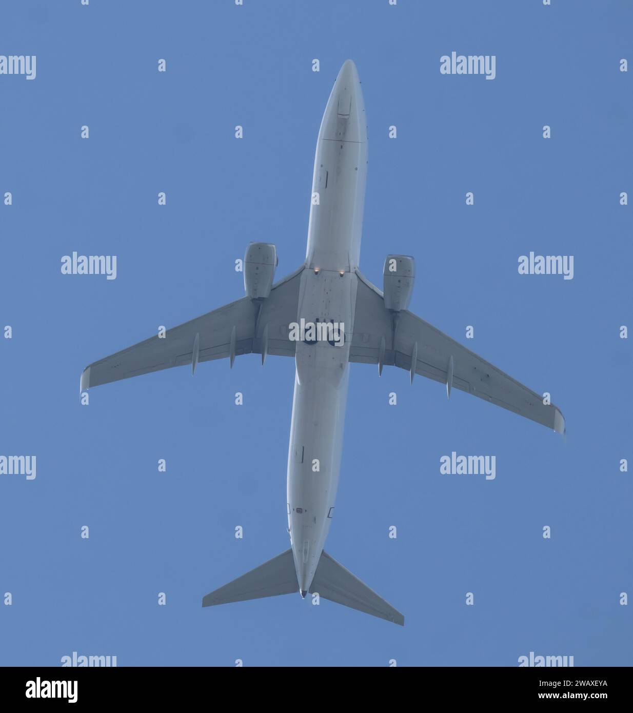 Low angle view of White Airplane flying under blue sky Stock Photo - Alamy