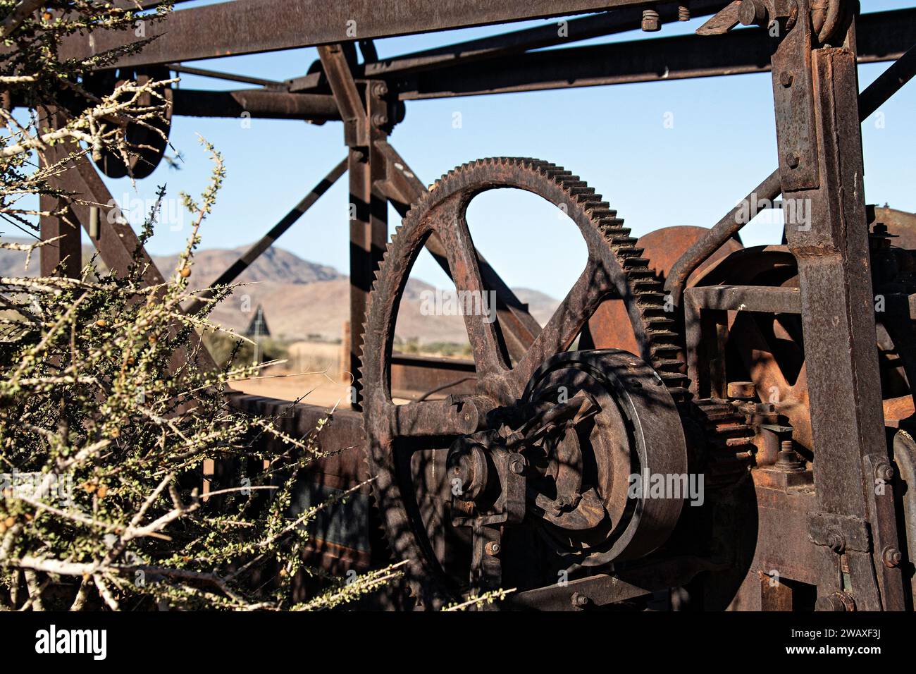 Rusty gear wheels of an old threshing machine standing in the desert at ...