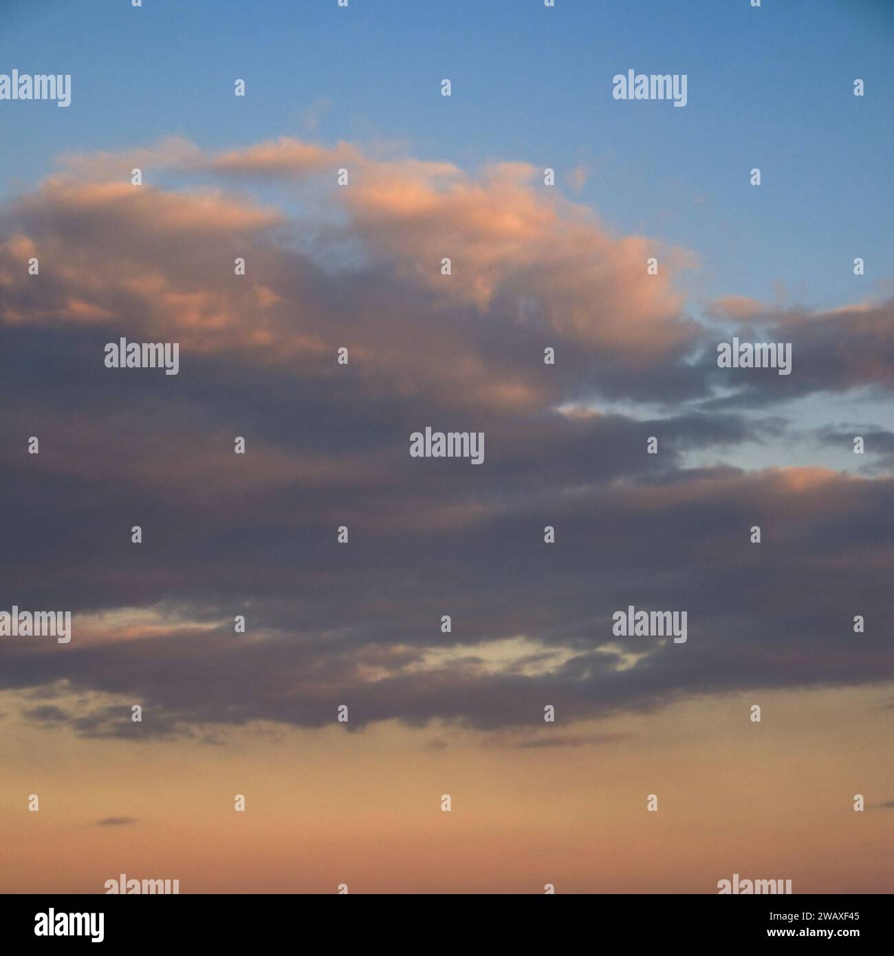 A serene sky with gentle clouds, illuminated by the fading sunlight ...