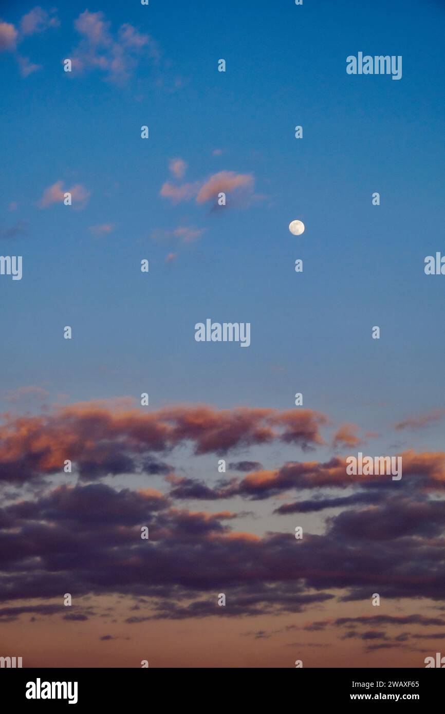 A clear evening sky with the moon visible, surrounded by dark clouds ...