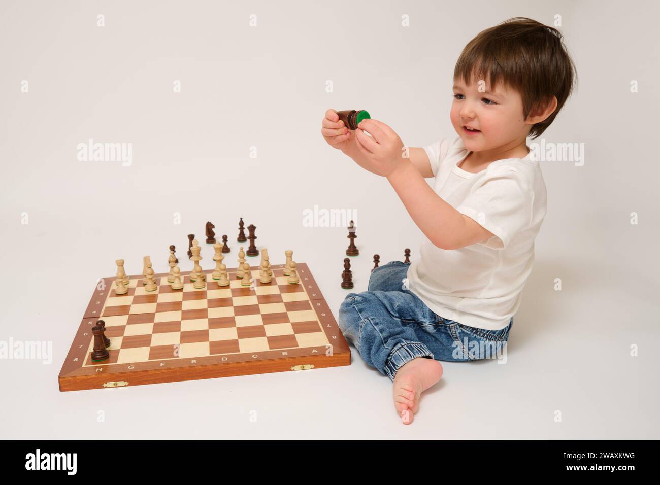 Toddler baby playing chess, studio white background. A child with chess ...