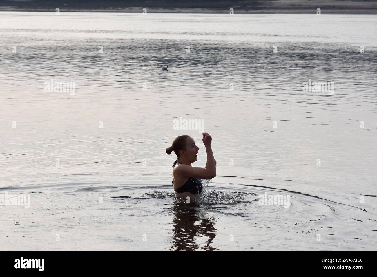 A woman prays as she dips in cold water of the Dnipro river during the ...