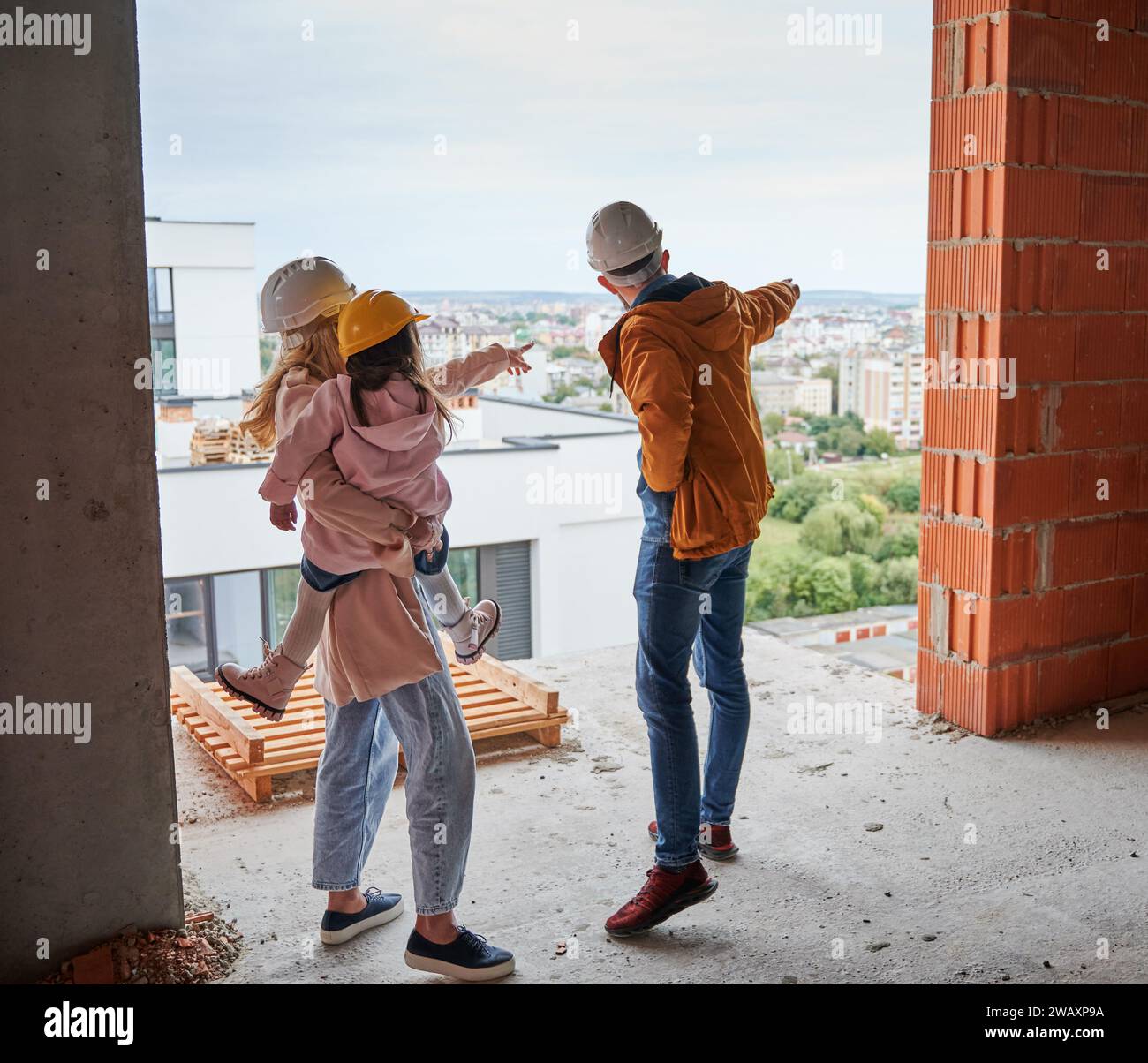 Back view of parents with daughter standing inside apartment building ...