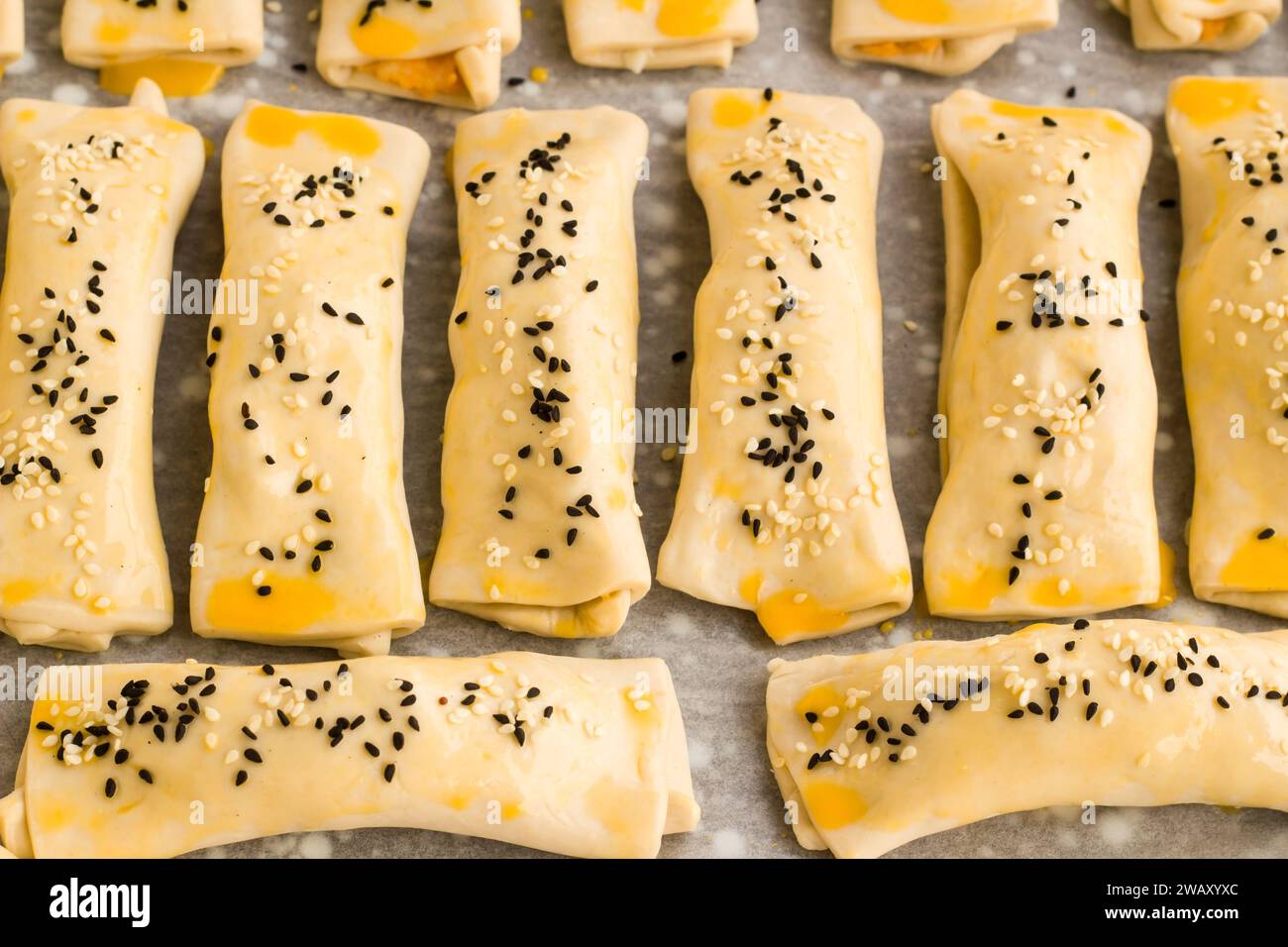 Rolled, puff pastry, brushed with egg yolk, ready to bake in oven Stock ...