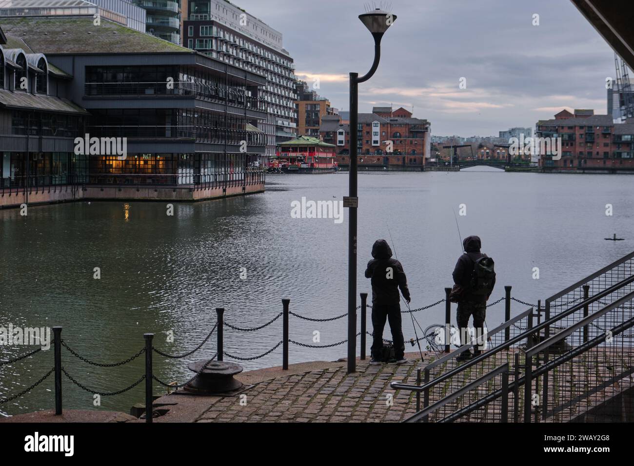 Urban fishing. Two men fishing in Millwall Inner Dock, South Quay ...