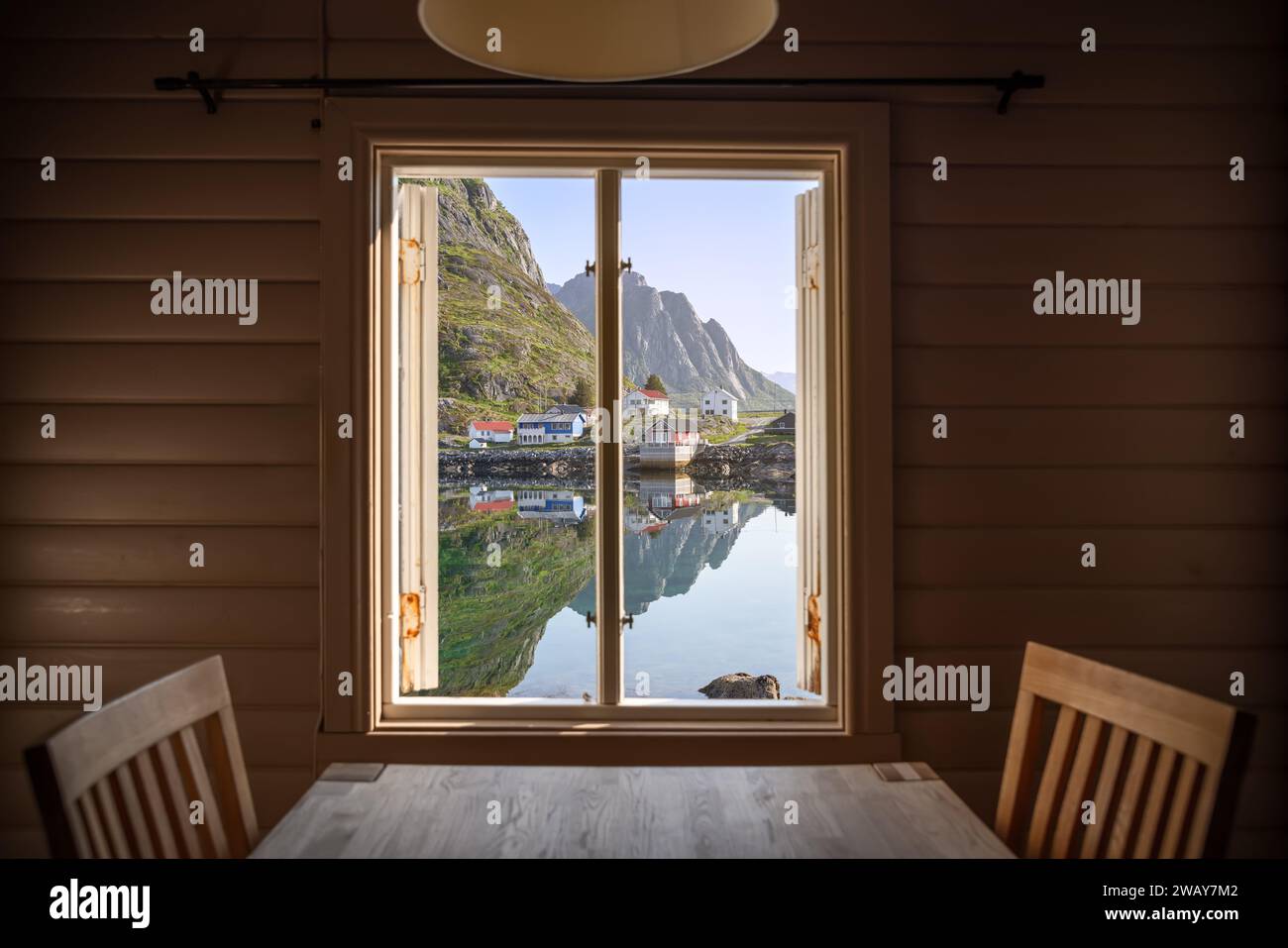 Through a Rorbu window, serene waters reflect the rugged beauty of ...