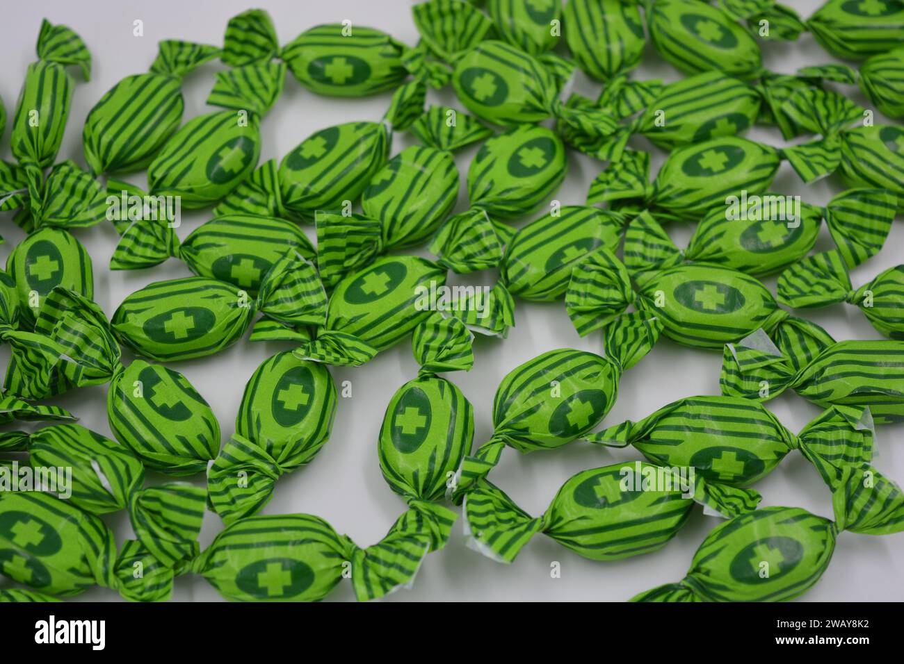 Bright, colorful factory menthol candies packed in green packaging with ...