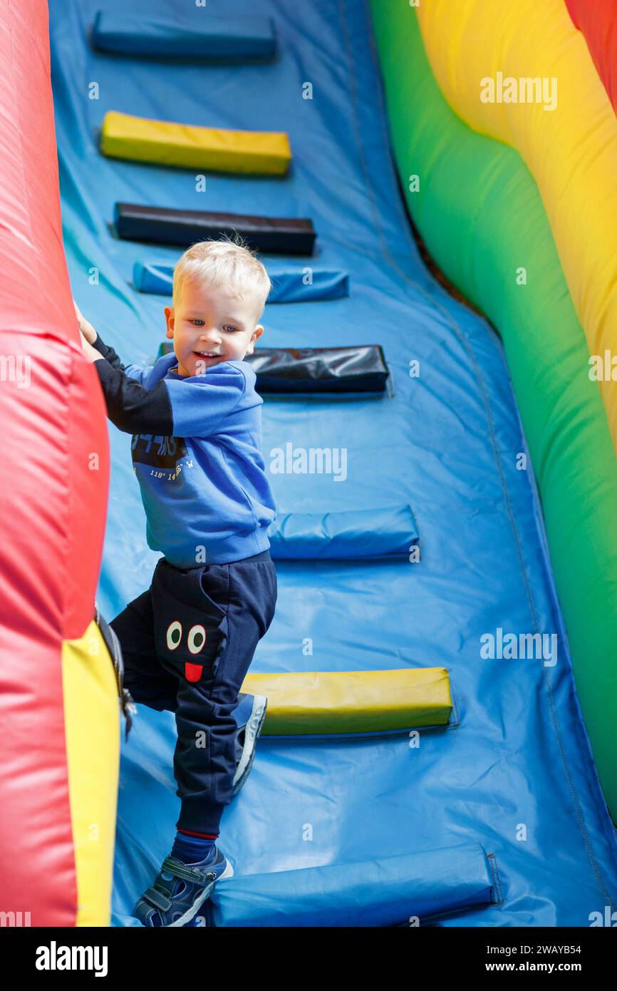 Little brave boy child climbs the stairs of a multi-colored slide in ...