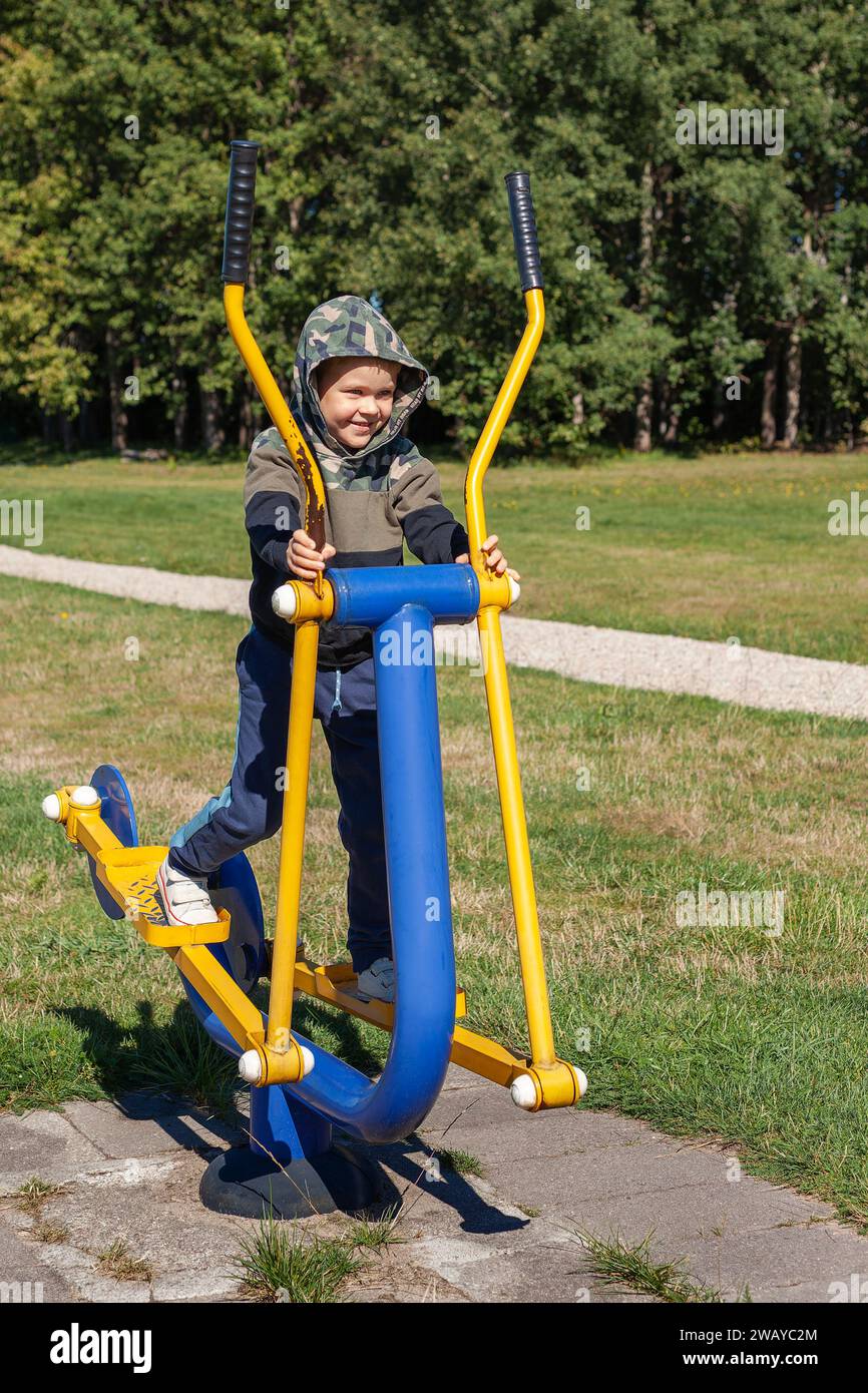 Happy little child treadle pedals on outdoor exercise elliptical bike ...