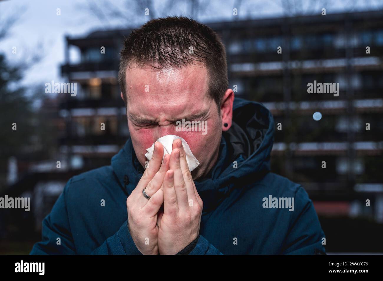 Bavaria, Germany - January 6, 2024: A sick man with a cold blows his ...
