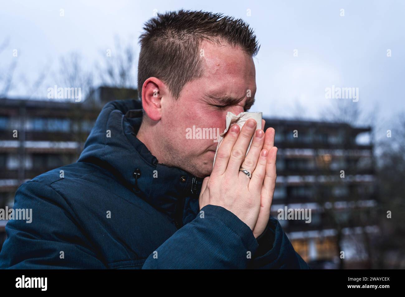 Bavaria, Germany - January 6, 2024: A sick man with a cold blows his ...