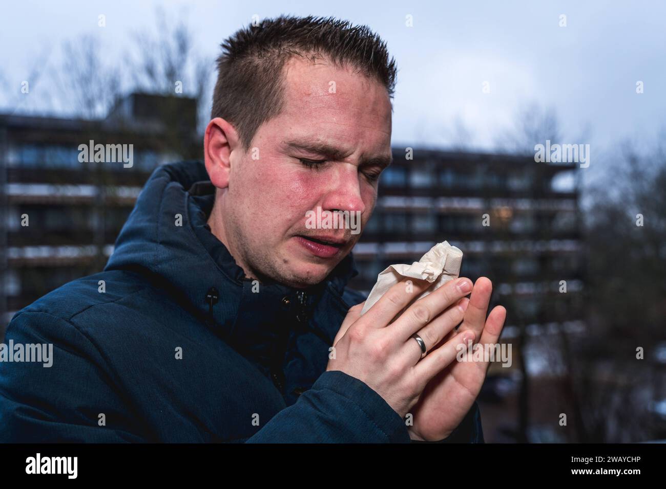 Bavaria, Germany - January 6, 2024: A sick man with a cold blows his ...