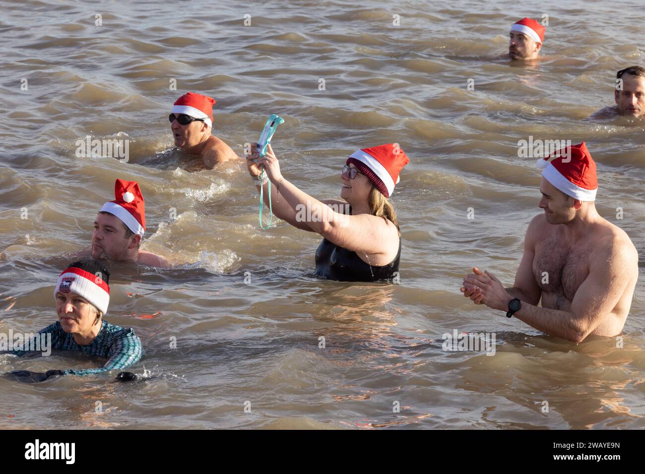 Woman takes a selfie whilst in the sea with other swimmers at the ...