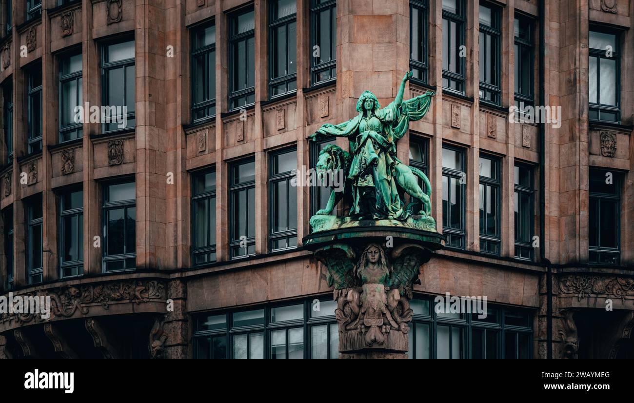 A bronze sculpture stands atop a city building, overlooking a busy ...