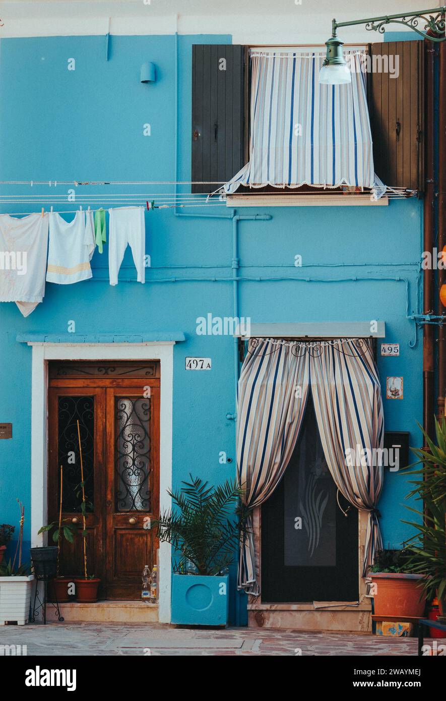 A vibrant blue-colored building with a white doorway adorned with sheer ...