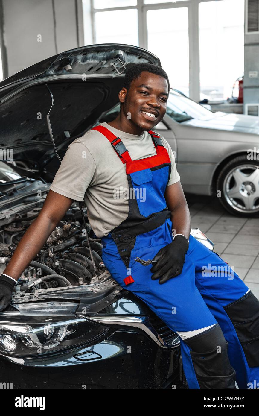 Young African man working under the hood of car fixing engine in auto ...