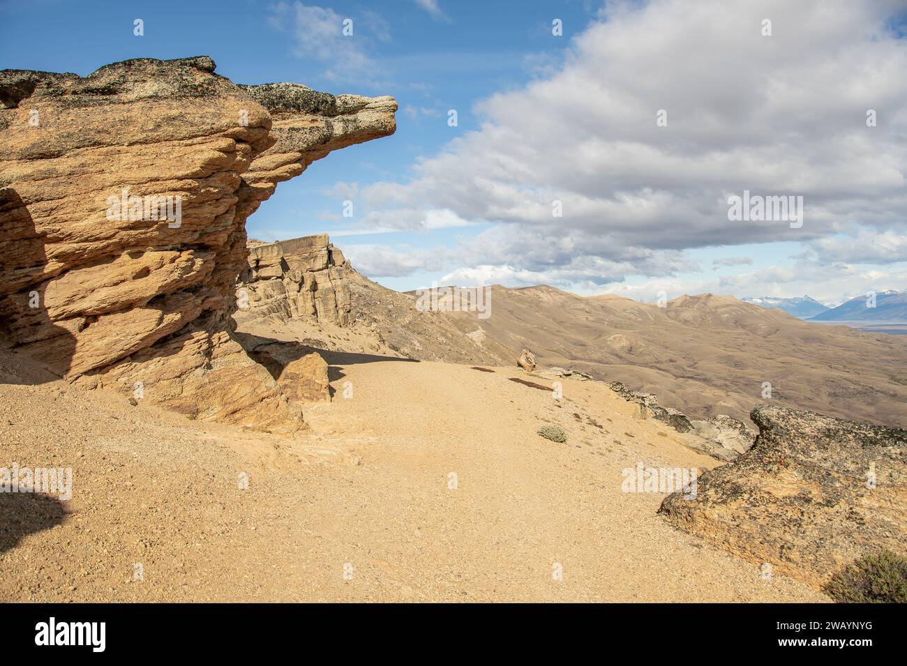 A barren desert trail meandering amongst rocky and gravel terrain, with ...