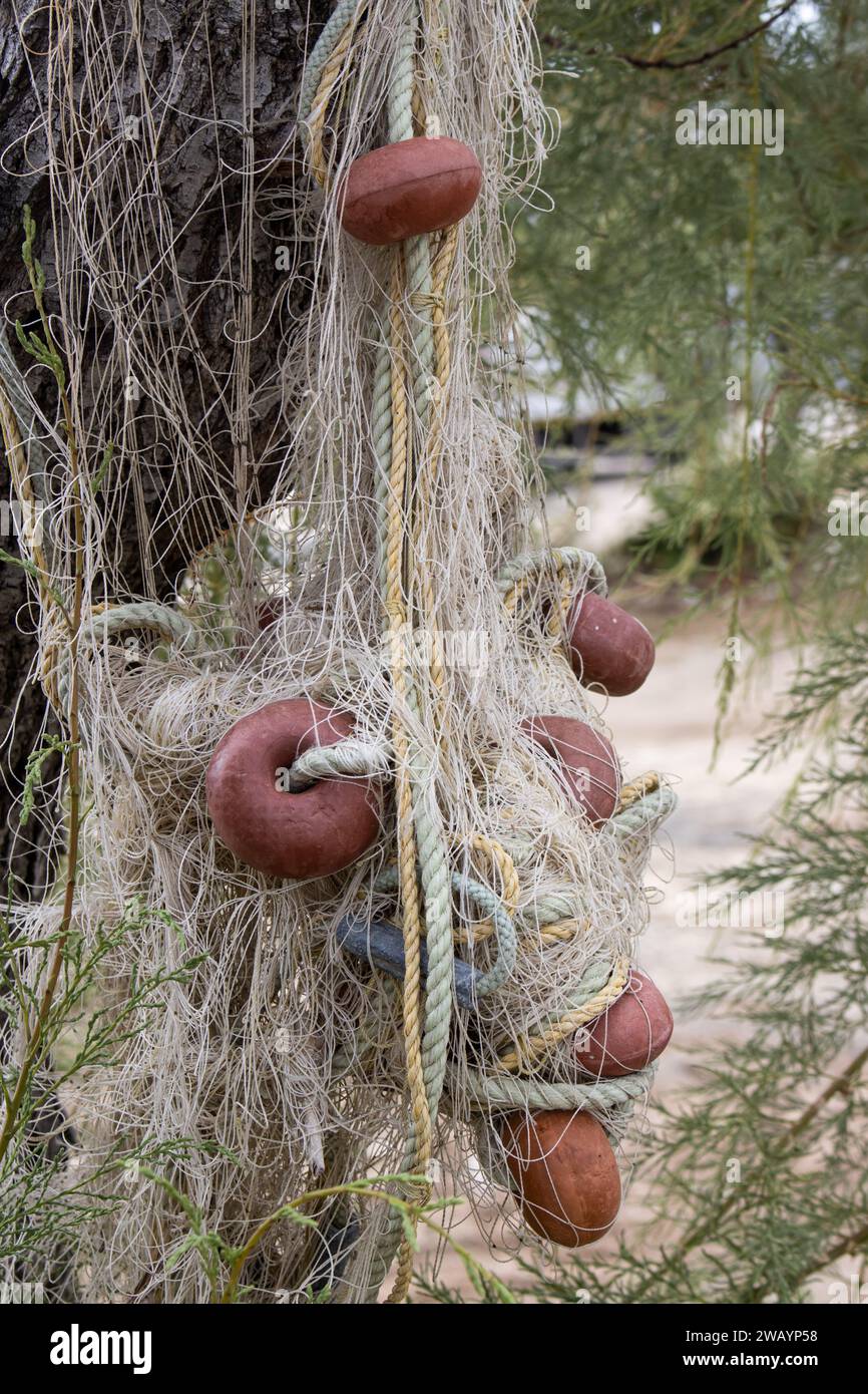 Old knotted fishing net hanging on a tree to dry. Small buoys. Green ...