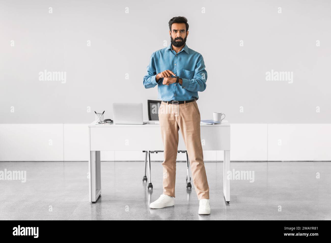 Indian businessman checking time, standing by office desk Stock Photo ...