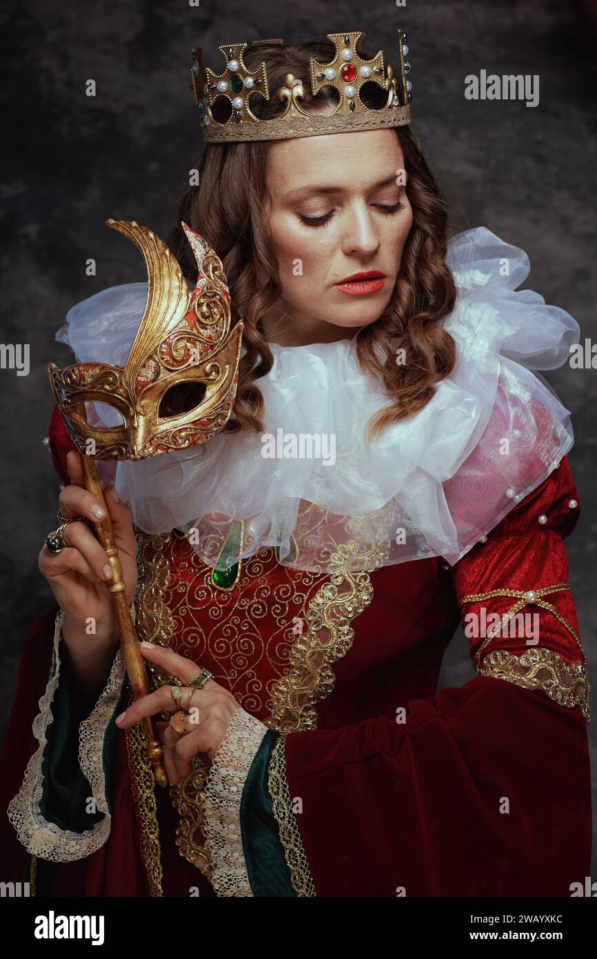 medieval queen in red dress with venetian mask, white collar and crown ...