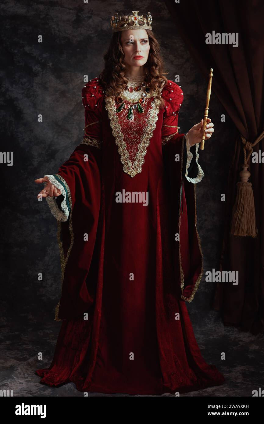 Full length portrait of medieval queen in red dress with wand and crown ...
