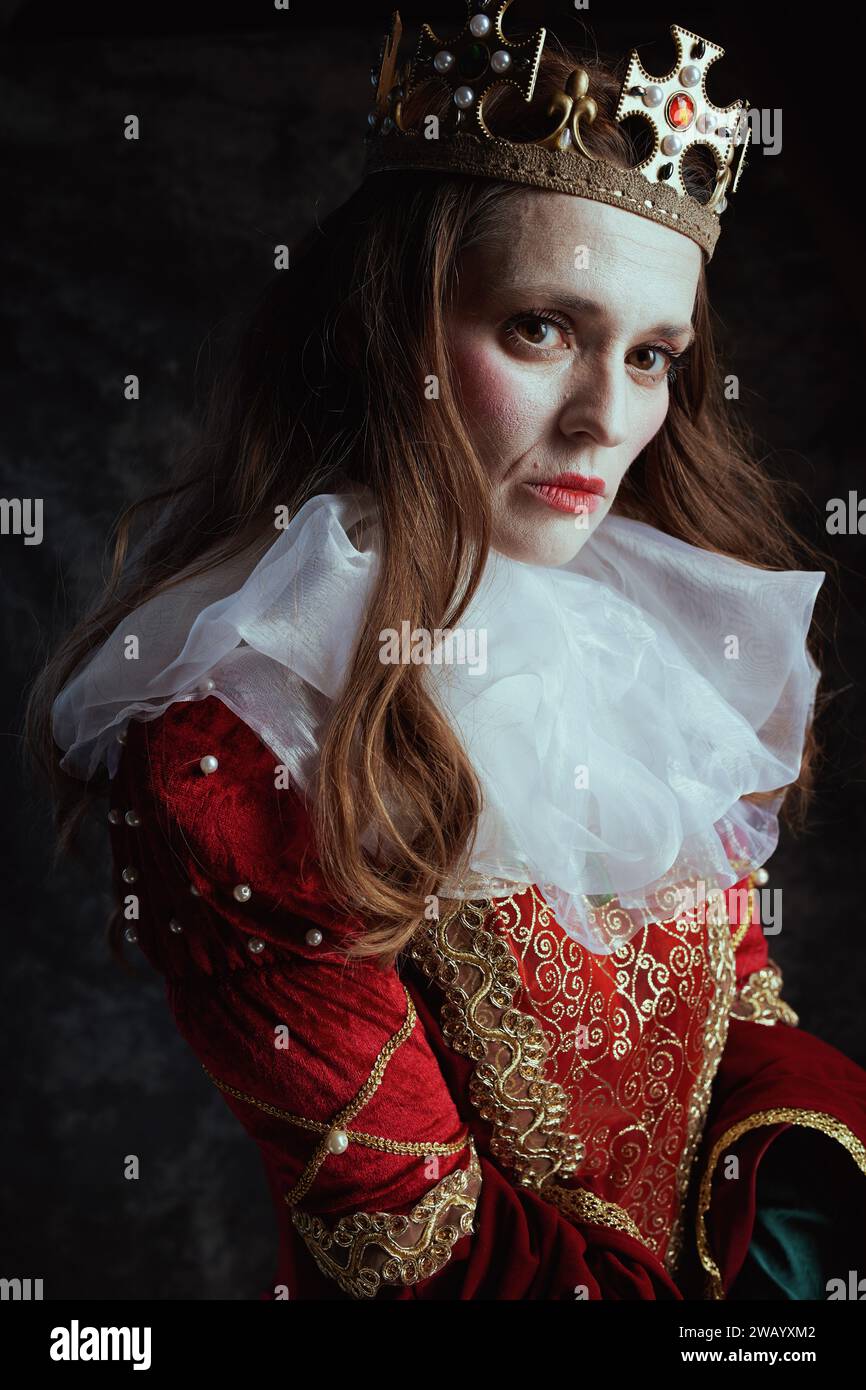 medieval queen in red dress with white collar and crown on dark gray ...
