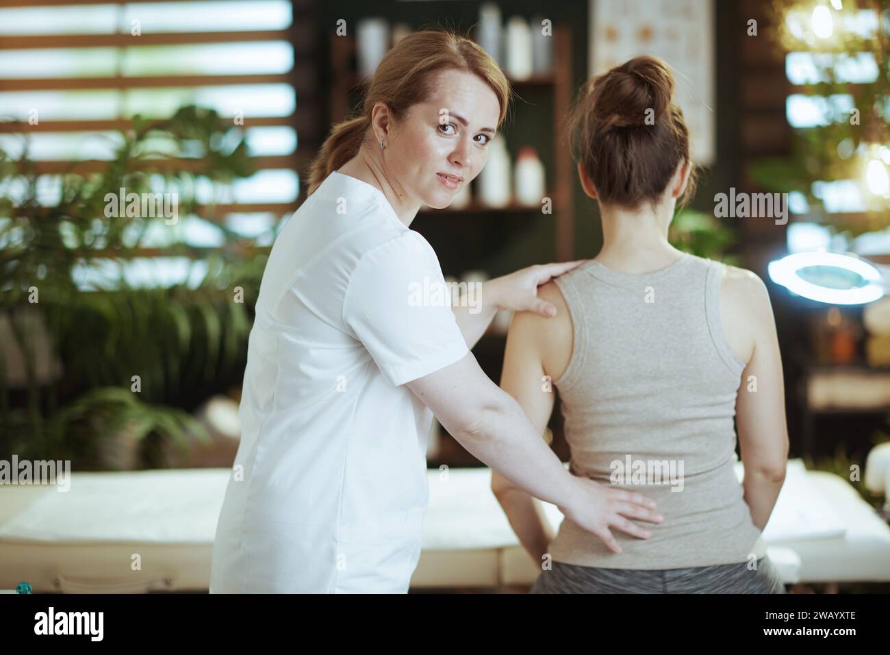 Healthcare time. medical massage therapist in spa salon checking clients back condition during ...