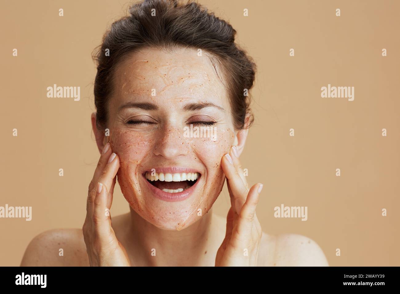 Portrait of smiling modern 40 years old woman with face scrub against ...