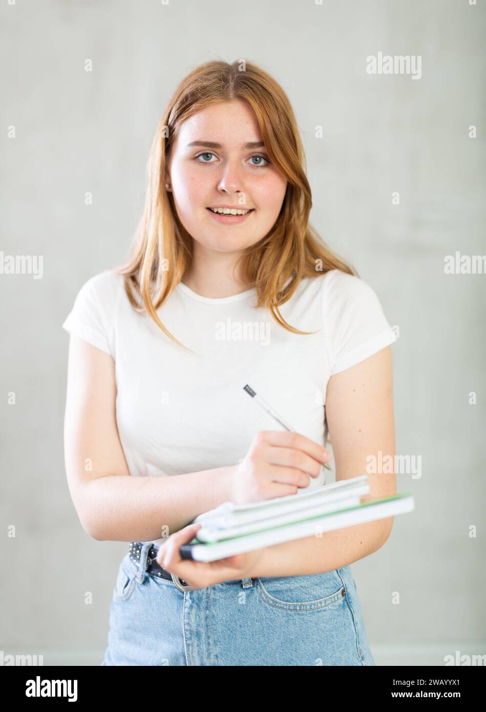 Positive girl student makes notes in notebook. Education in high school ...