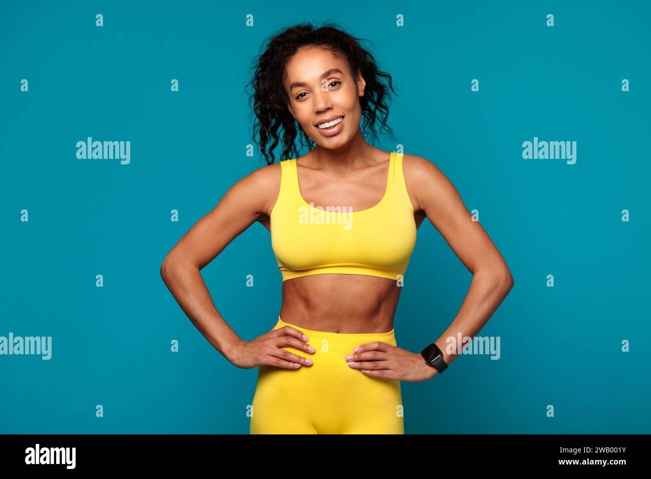 african fitness lady in yellow sportswear smiling over blue background ...