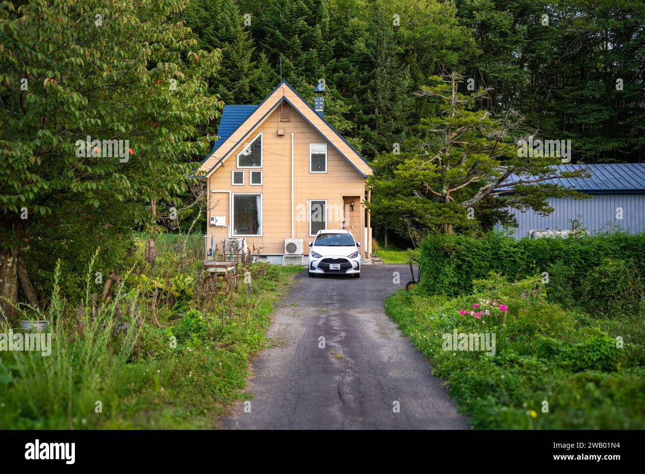 compact japanese car sitting in front of a small farm house at the end ...