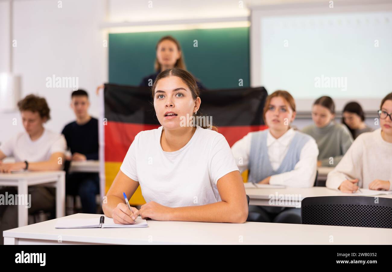 High school teacher holds the flag of Germany in her hands and talks ...