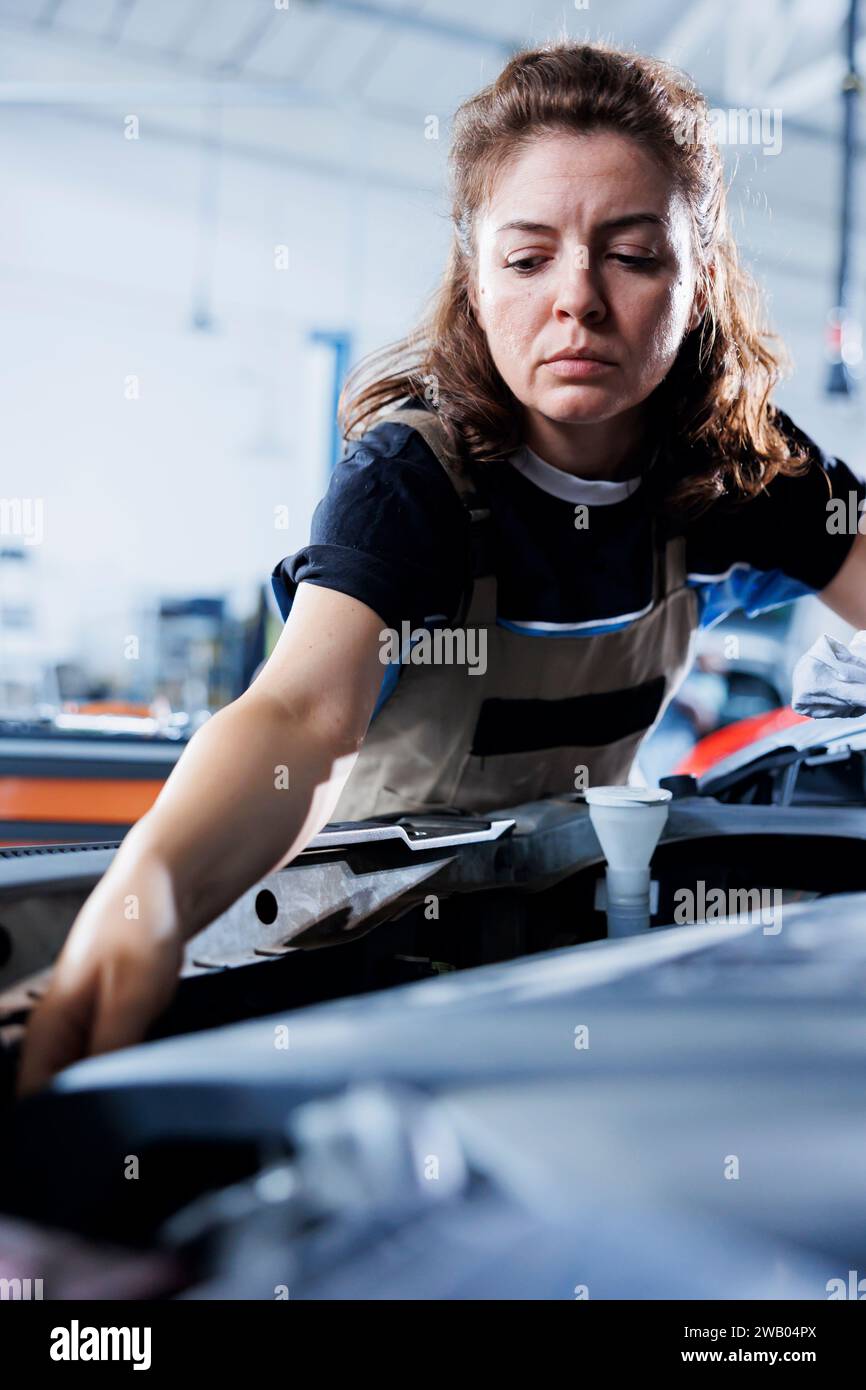 Licensed mechanic in garage finishing repairing car, looking underneath ...