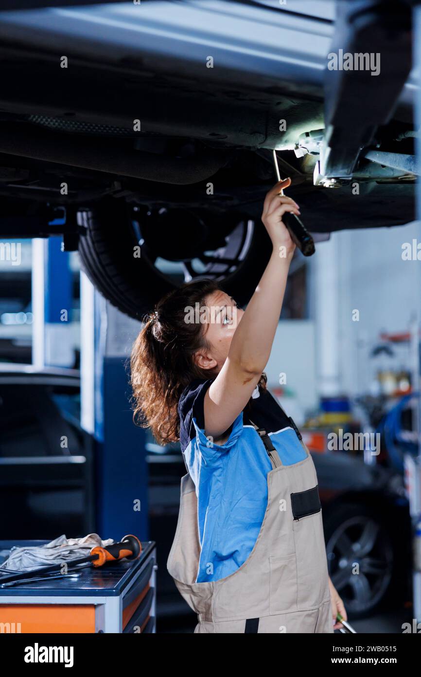 Seasoned mechanic working on suspended car in garage, checking engine ...