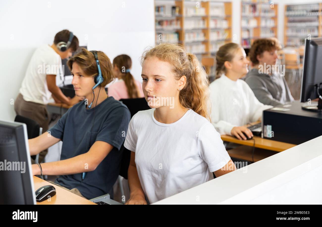 Pupils using computers at lesson, teacher teaching them in class room ...